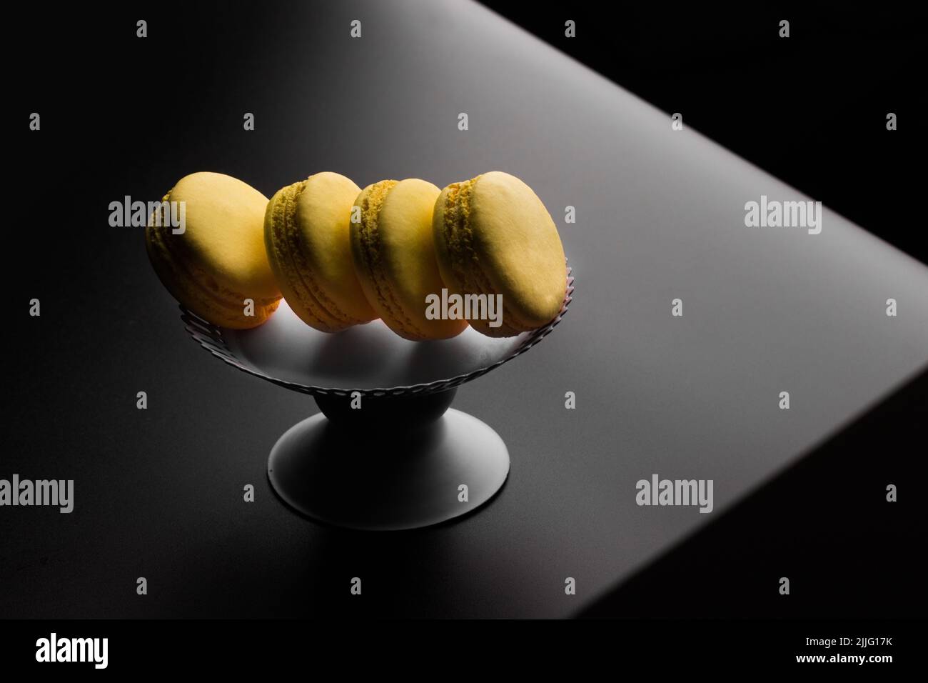 Yellow Macarons on a black background French pasta. Stack of yellow ...