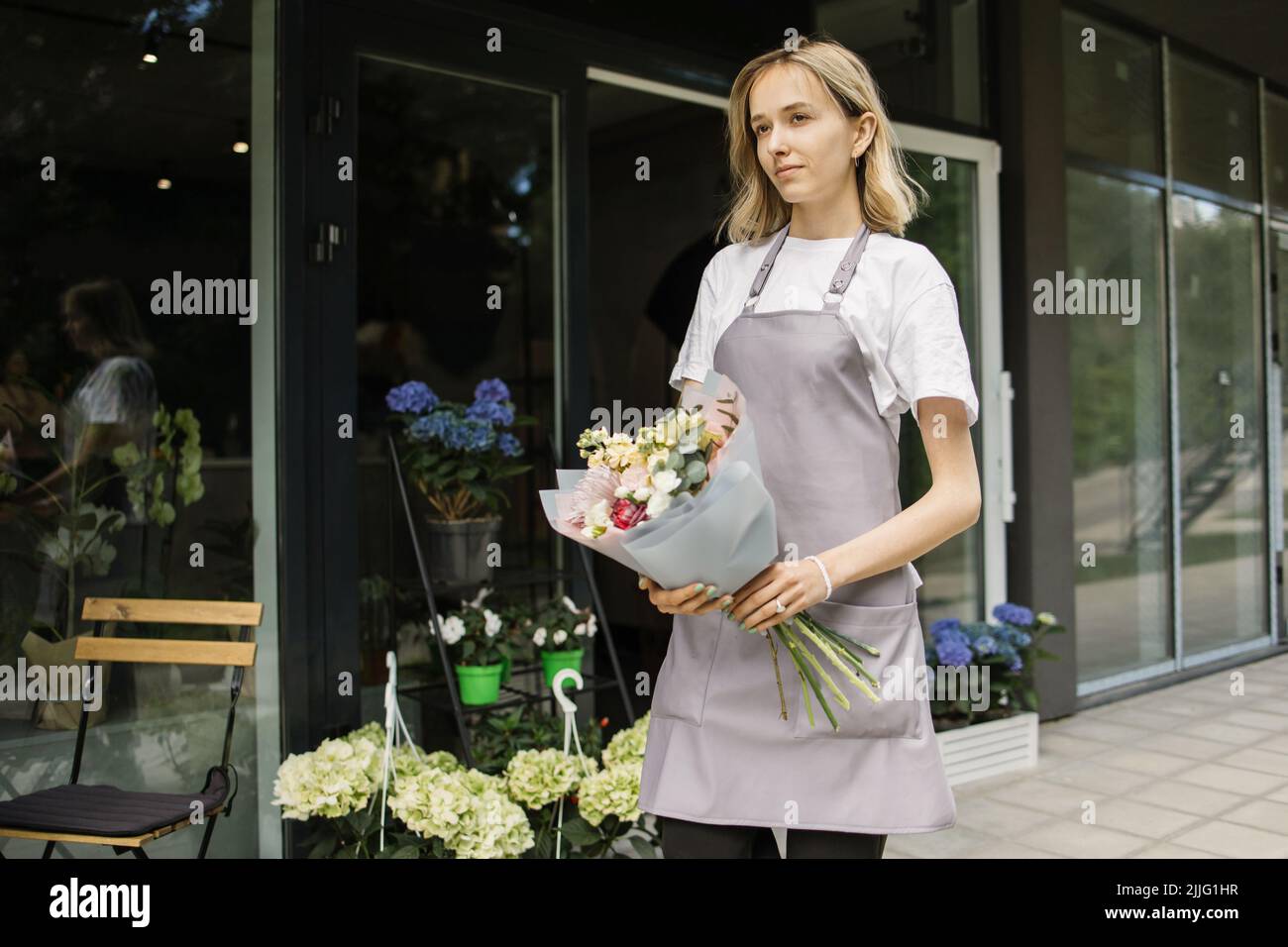 Portrait of smiling male florist standing in front of flower shops ...
