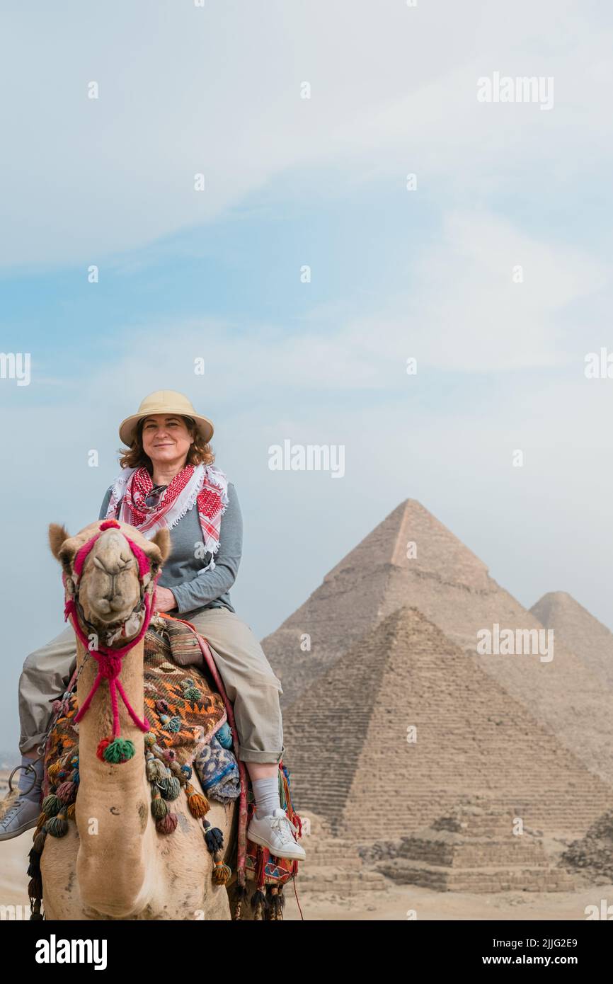 tourist woman riding a dromedary in front of pyramids. Egypt, Cairo ...
