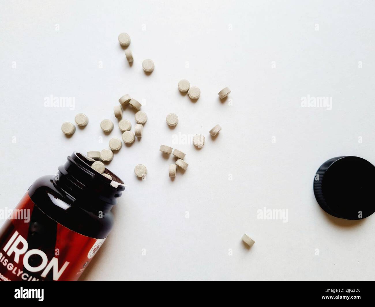 From the inverted jar, iron supplement pills come out onto the white ...