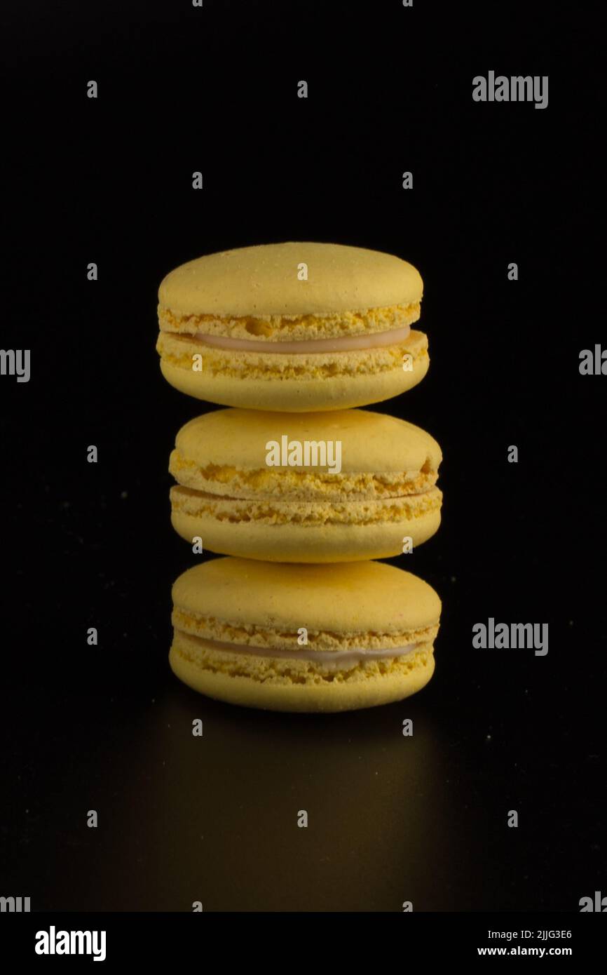 Yellow Macarons on a black background French pasta. Stack of yellow ...