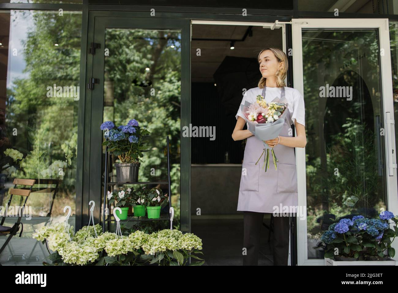 Business Woman near flower shop door. Photo of beautiful woman standing ...