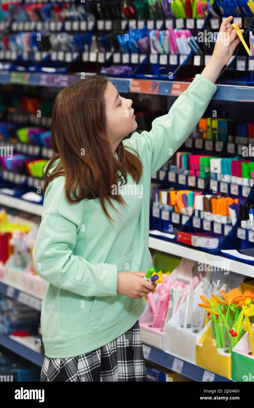 girl choosing school supplies on rack in stationery store Stock Photo ...