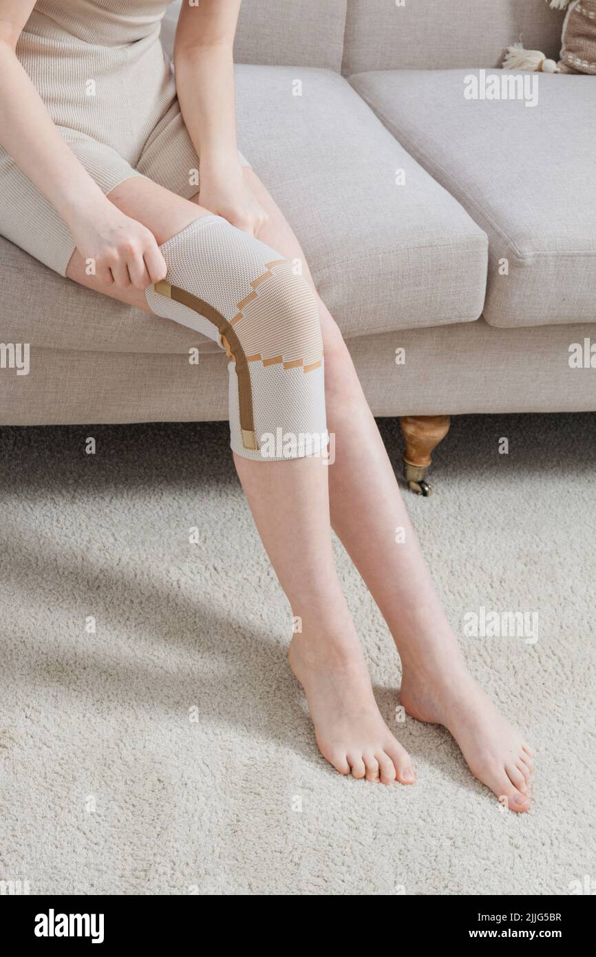 Knee support brace on a woman leg. girl in an orthosis in the interior ...