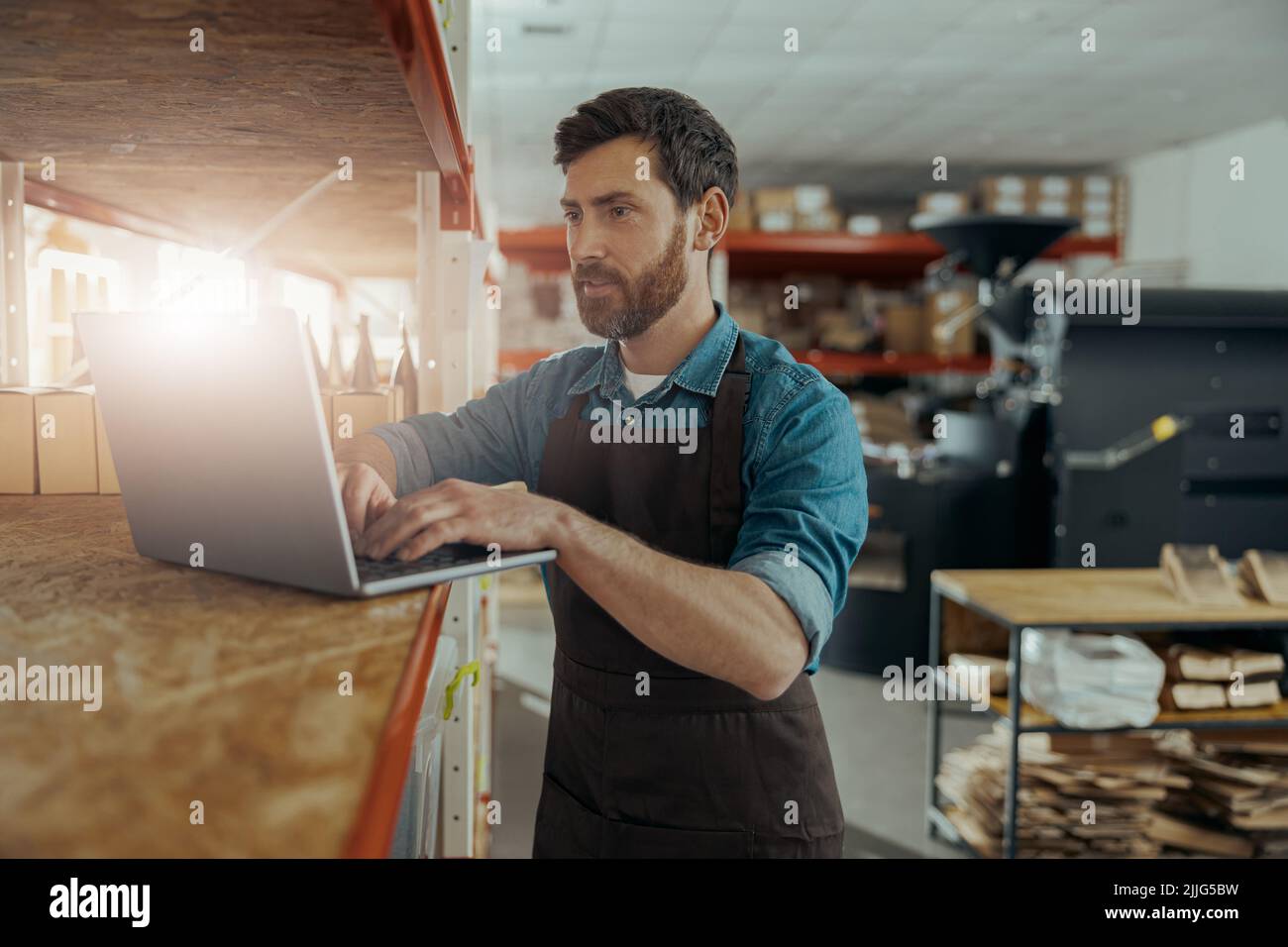 Warehouse worker in uniform standing on coffee small factory with ...