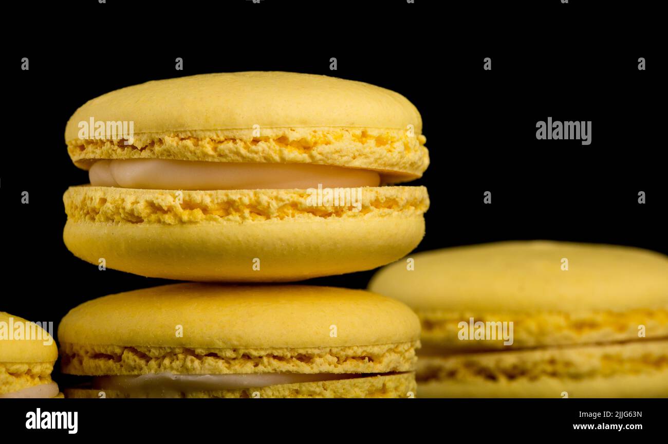 Yellow Macarons on a black background French pasta. Stack of yellow ...