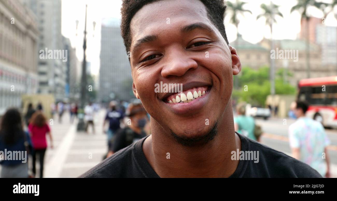 Trendy young black African man smiling at camera in downtown city, real ...