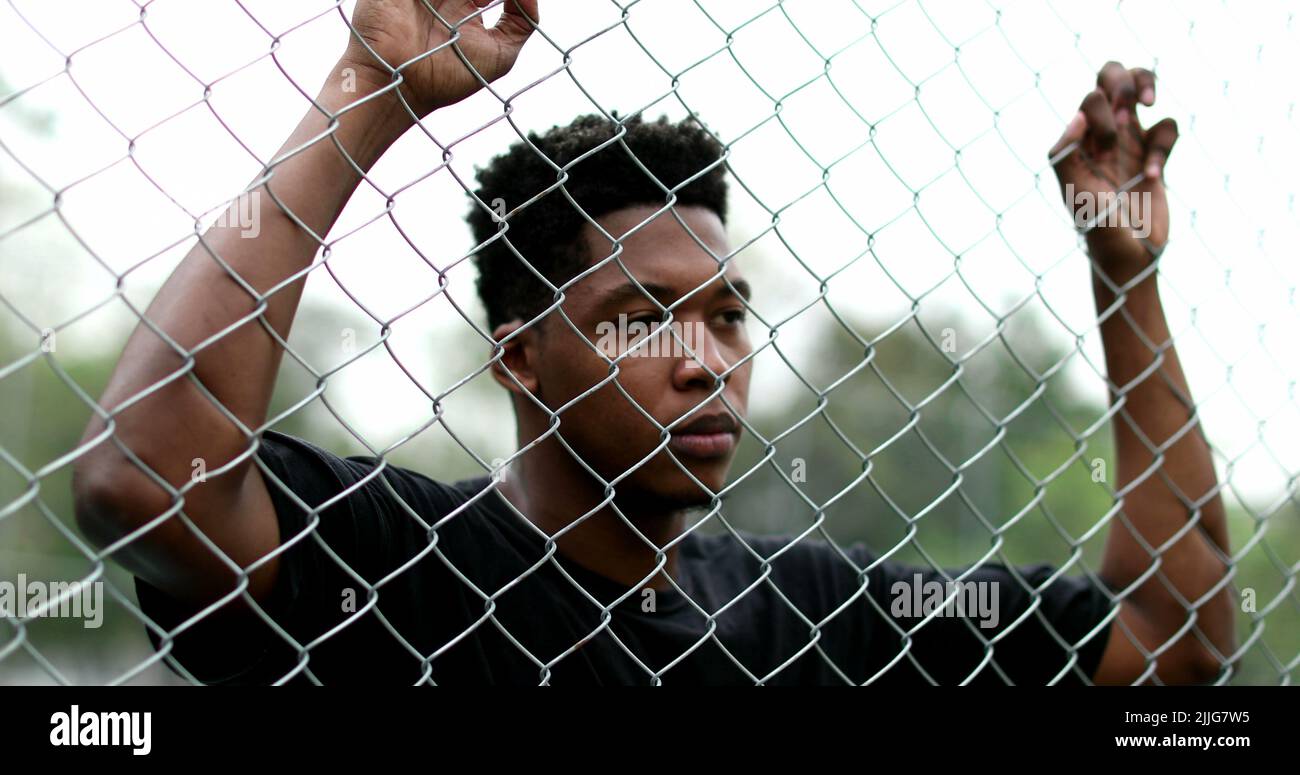 Young black African man leaning on metal fence Stock Photo - Alamy