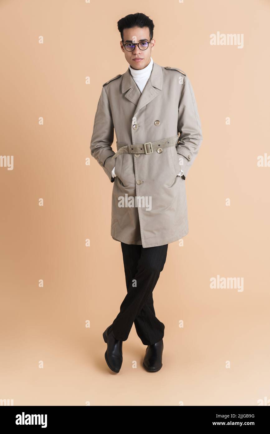 Young middle eastern man wearing coat posing and looking at camera ...