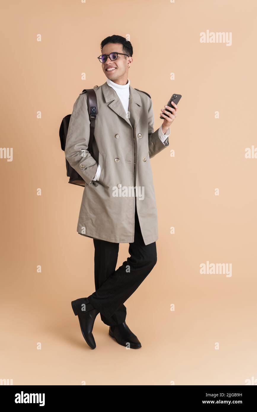 Young middle eastern man wearing coat using mobile phone isolated over ...