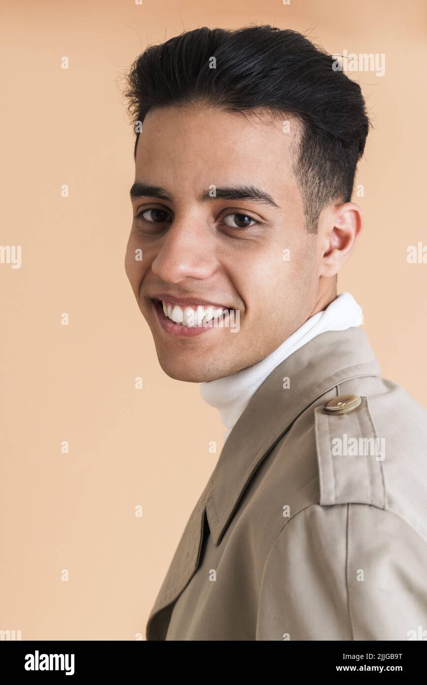 Young middle eastern man wearing coat smiling and looking at camera ...