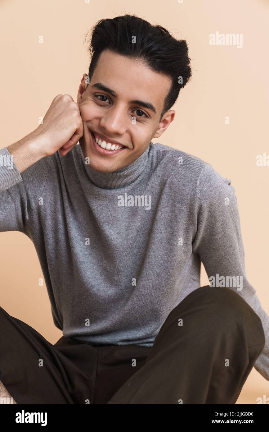 Young middle eastern man smiling while sitting on floor isolated over ...