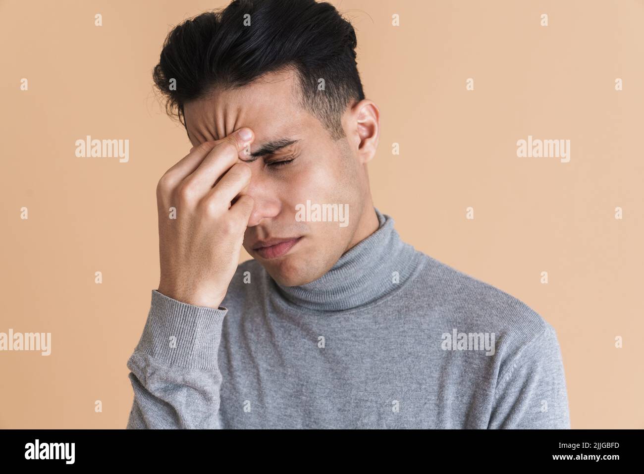 Young puzzled man with headache holding his forehead isolated over ...
