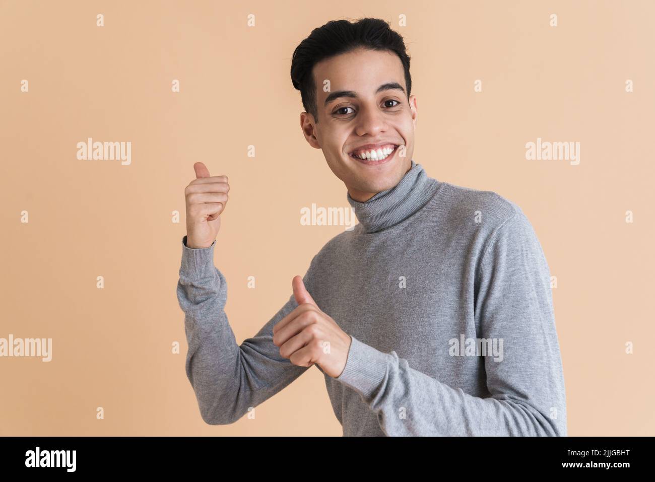 Young middle eastern man smiling while pointing fingers backward ...