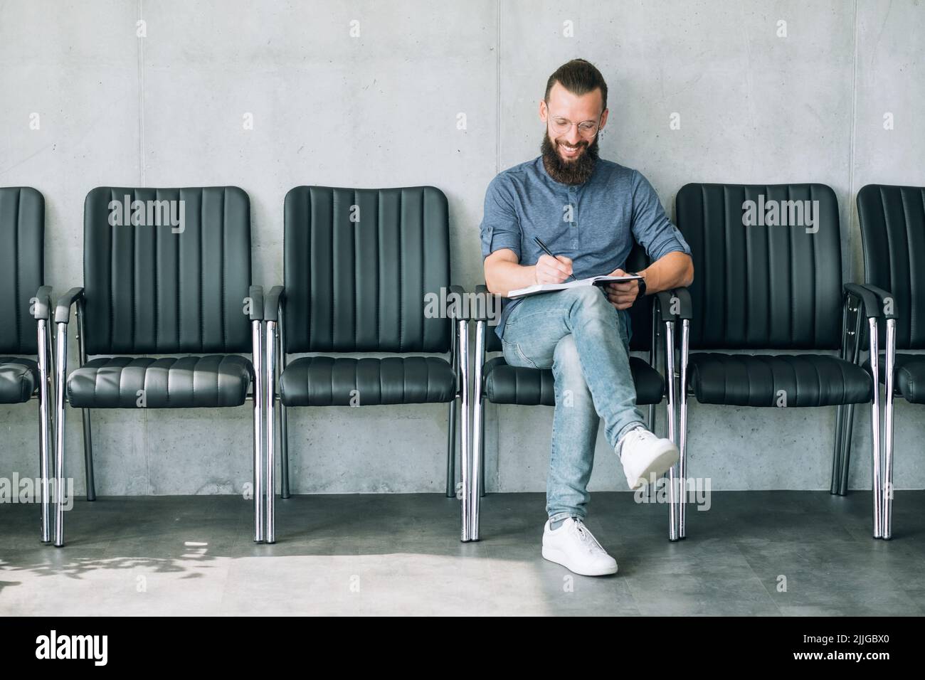 man sit row chairs write interview job application Stock Photo - Alamy