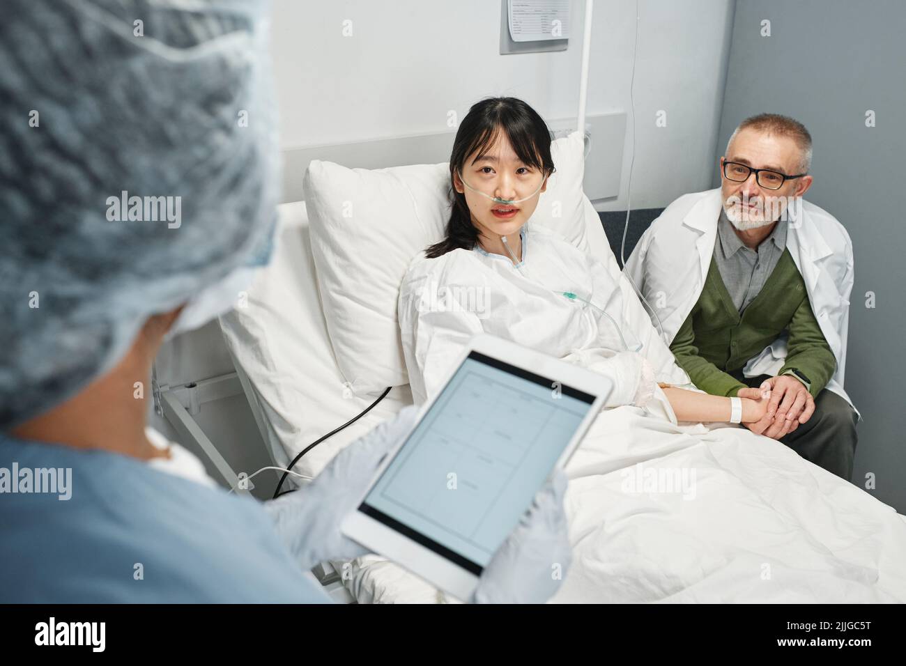 Unrecognizable doctor holding digital tablet talking to young Asian ...