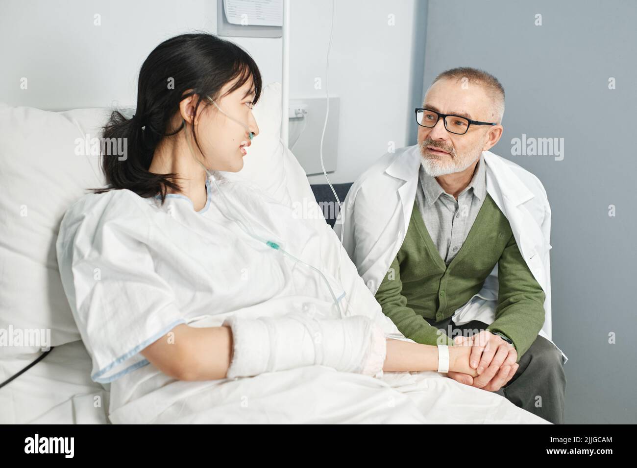 Loving father visiting his daughter in hospital sitting on chair ...