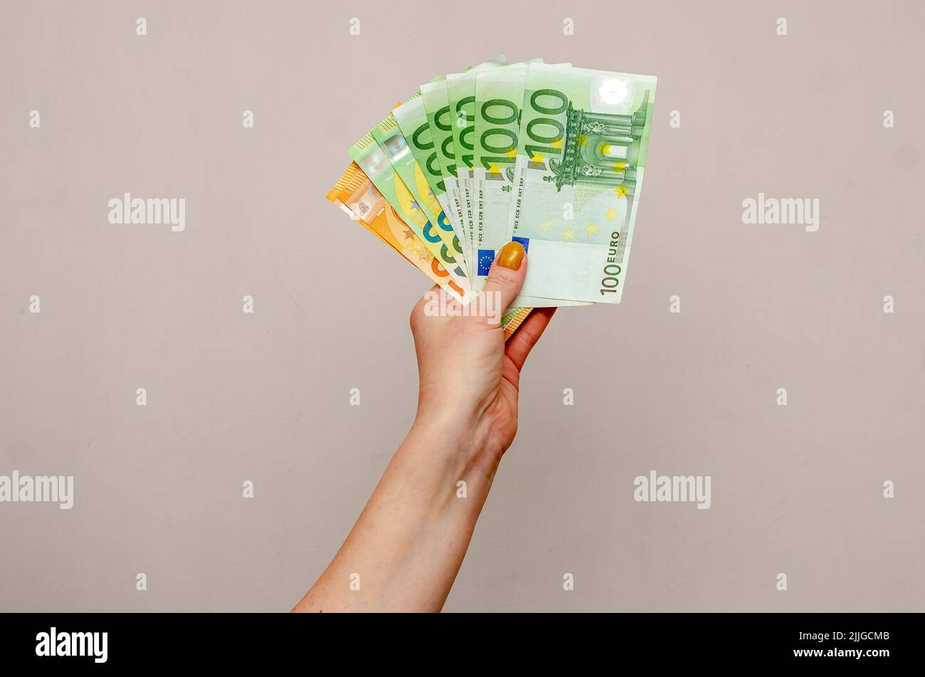 Woman holds euro cash in hand on light background Stock Photo - Alamy