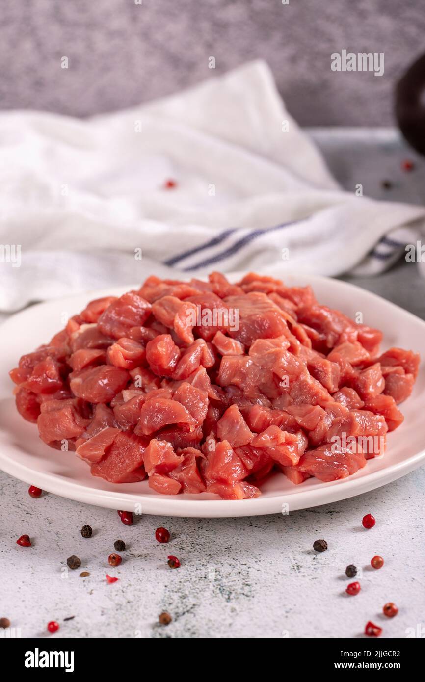 Cubed meat. Red meat in a chopped plate on a stone floor. Butcher ...