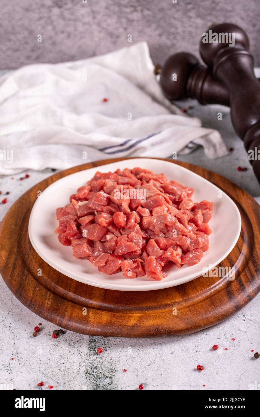 Cubed meat. Red meat in a chopped plate on a stone floor. Butcher ...