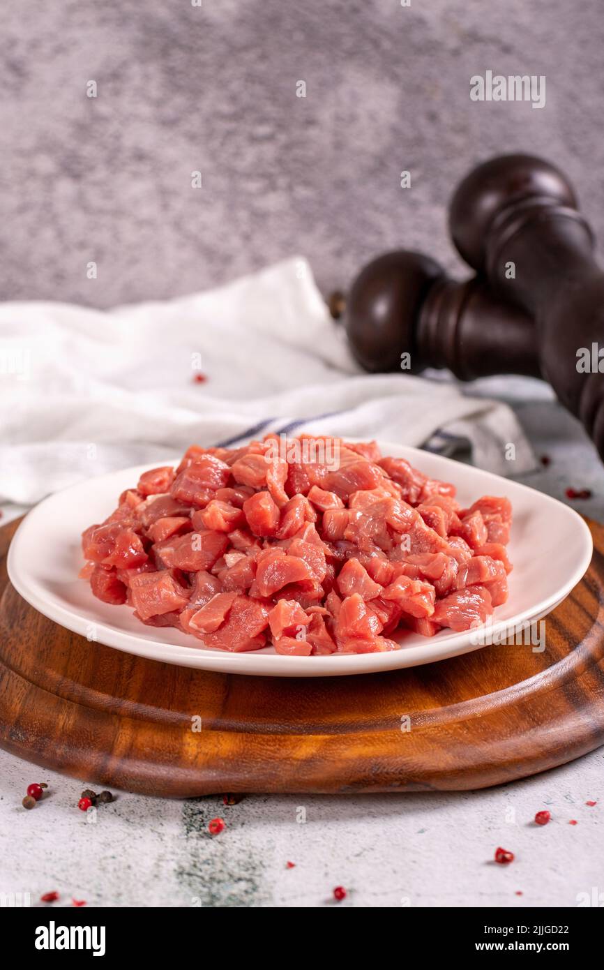 Cubed meat. Red meat in a chopped plate on a stone floor. Butcher ...