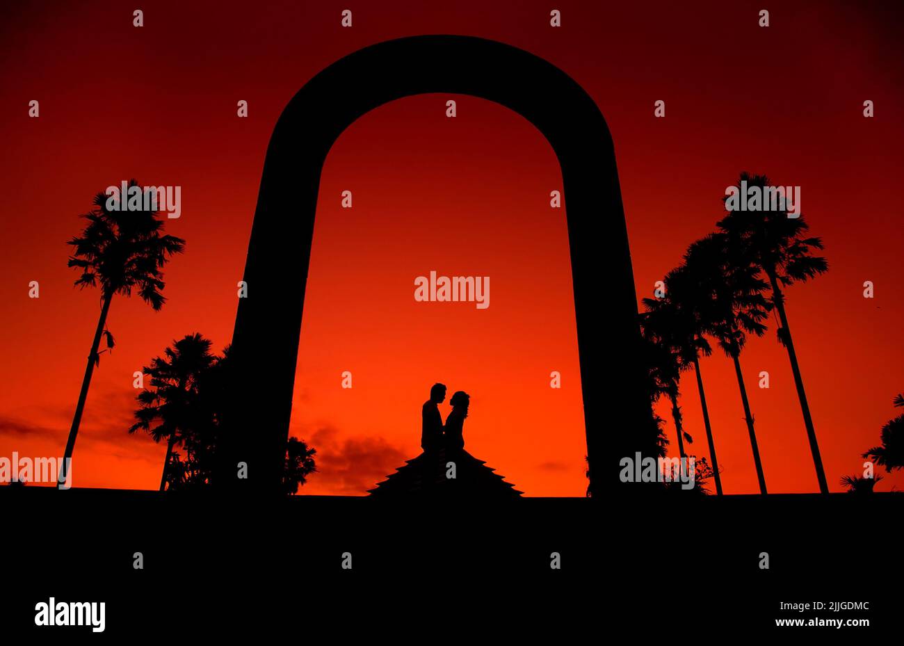 Beautiful silhouette of the bride and groom under the arch during ...