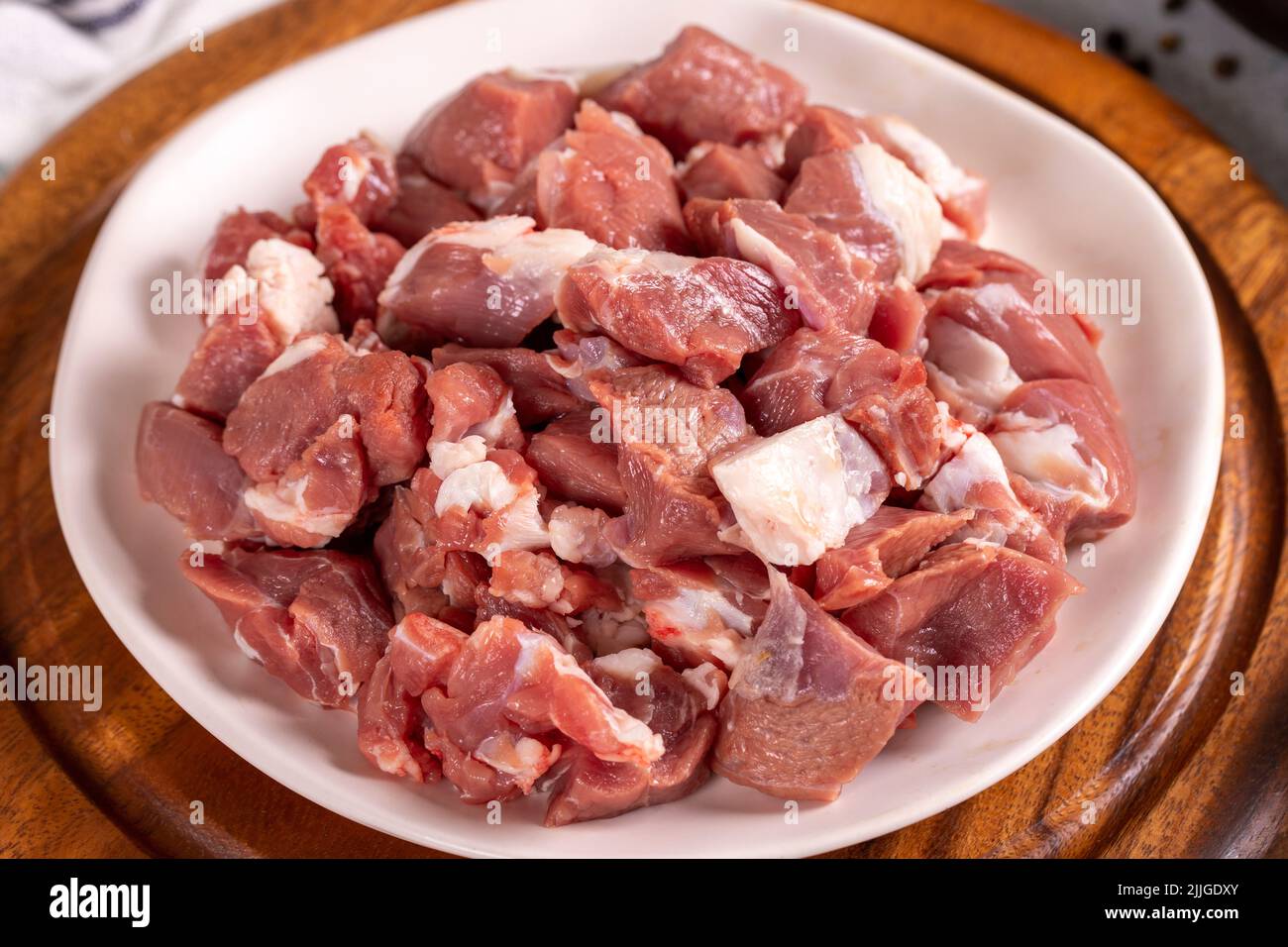 Lamb cubed meat. Chopped red meat in a plate on a stone floor. Butcher ...