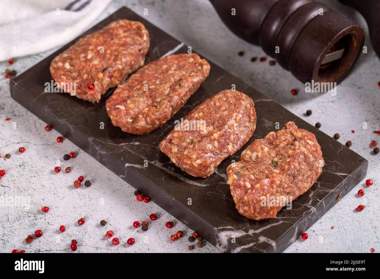Uncooked spicy grilled meatballs. Meatballs on a stone serving plate on ...
