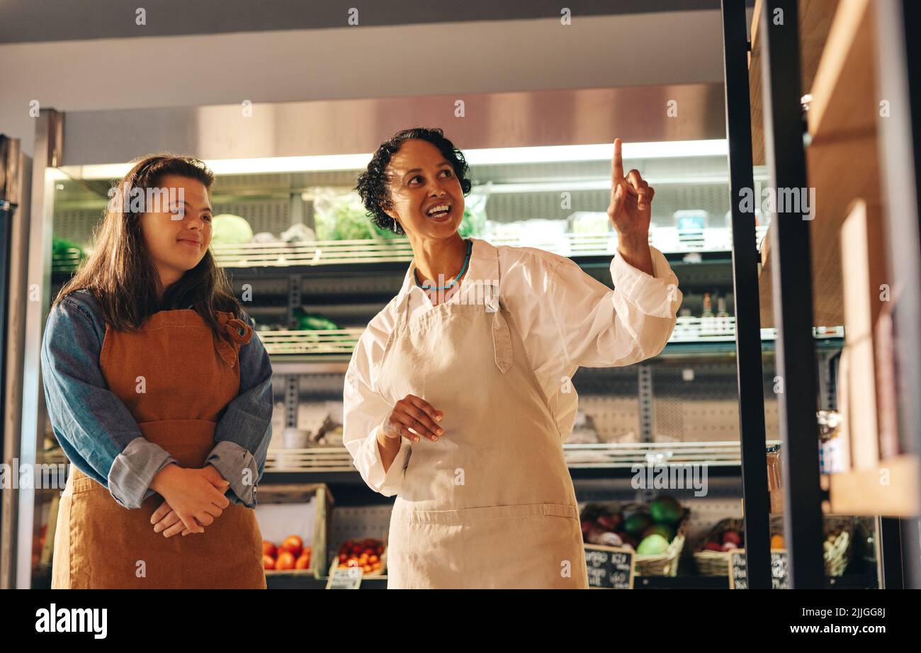 Mature grocery store supervisor giving instructions to her new employee ...