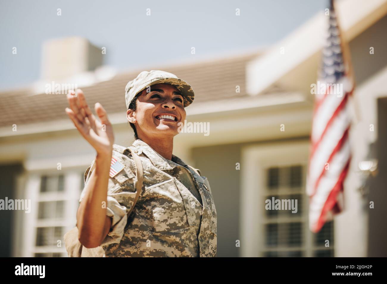 Cheerful female soldier smiling and waving her hand proudly while ...
