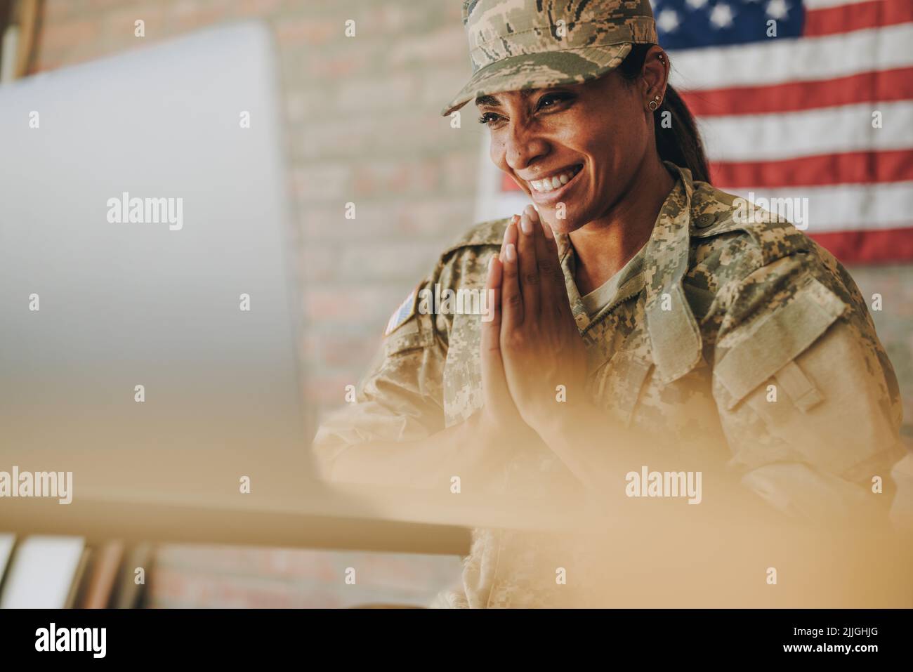 Cheerful female soldier smiling happily while video chatting with her ...
