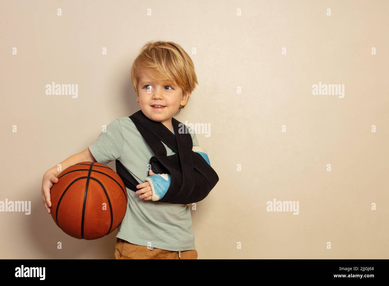Funny little blond boy with broken hand holding basketball ball Stock ...