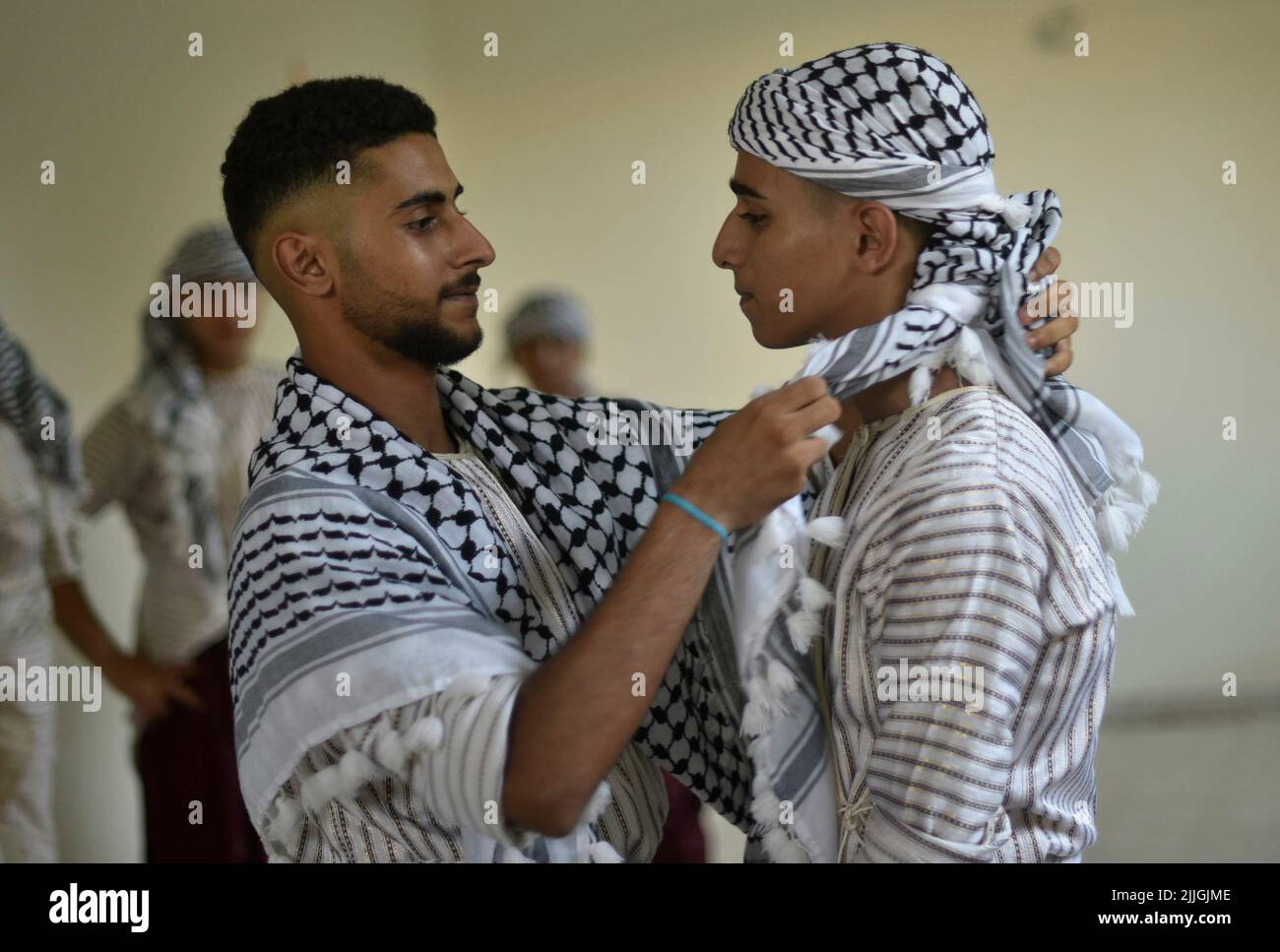 A Palestinian helps his friend with wearing the traditional costumes ...