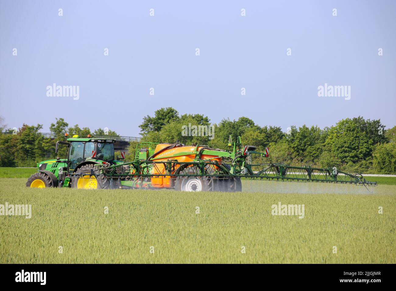 Farmer drives his tractor with crop protection sprayer over his wheat ...