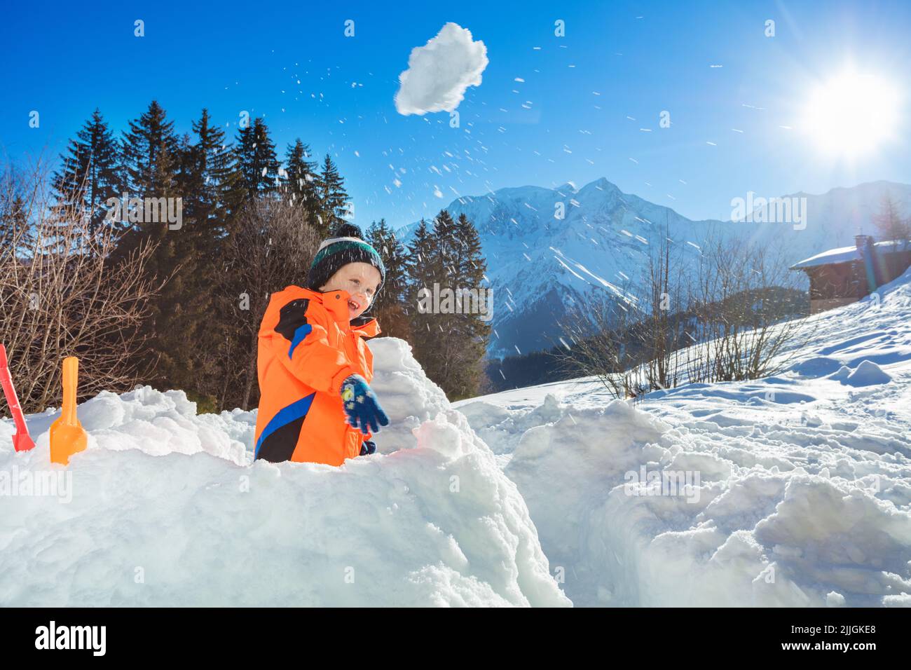 Happy cute boy throw snowball standing in the snow fortress Stock Photo ...
