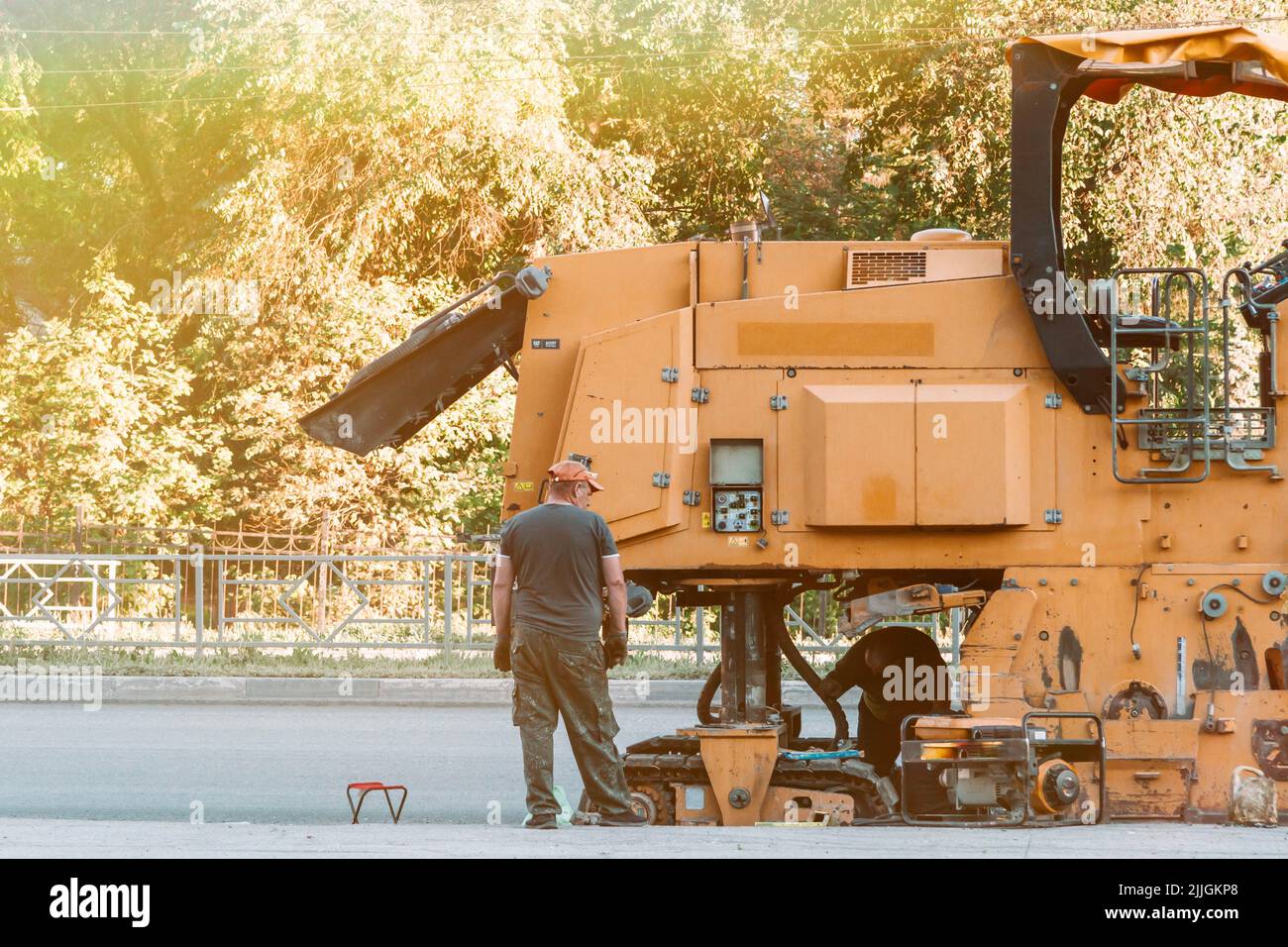 Road works. Workers repair the asphalt pavement of the road. Road ...