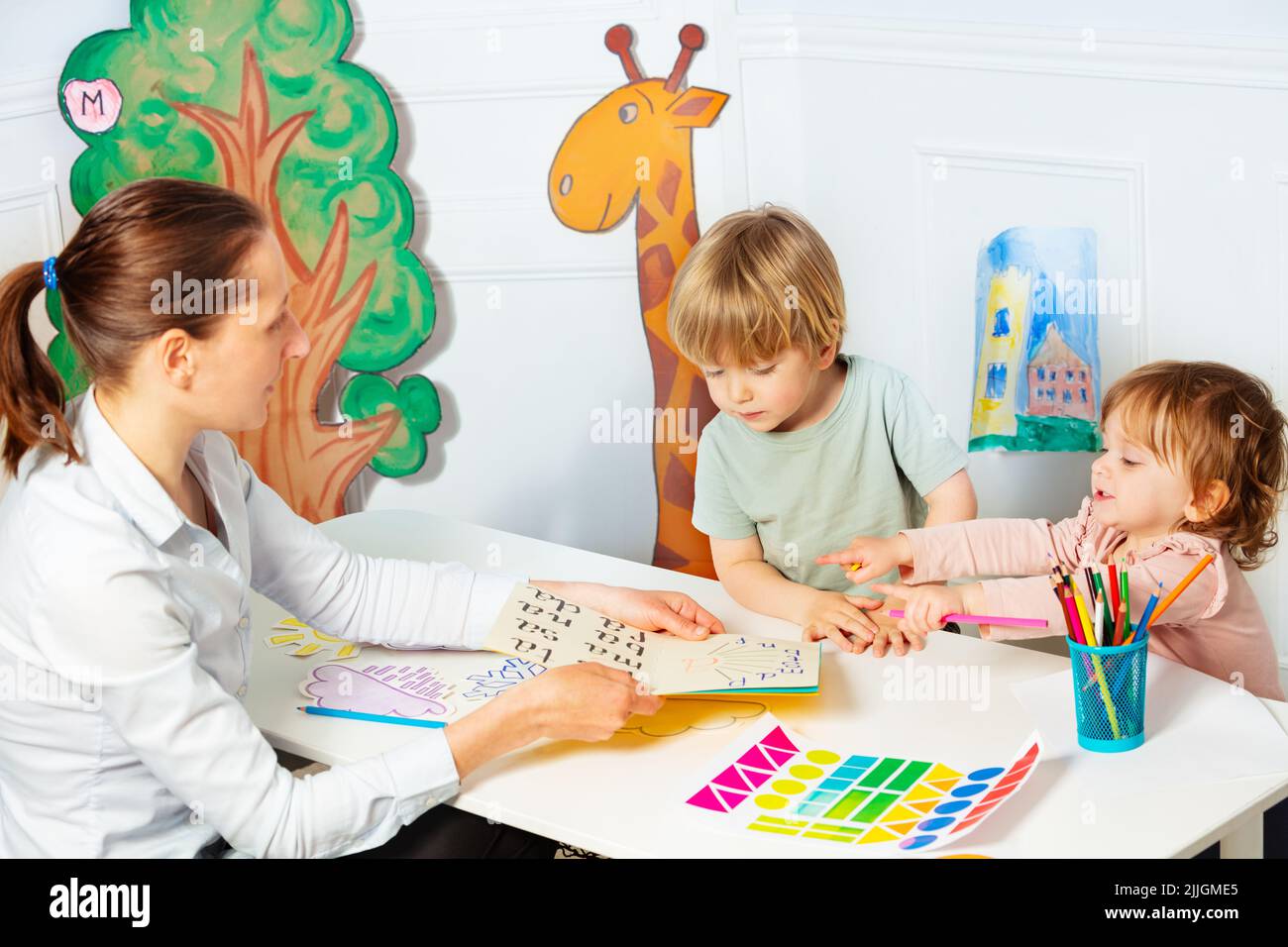 Mother teaches little kids to read letters in the book Stock Photo - Alamy
