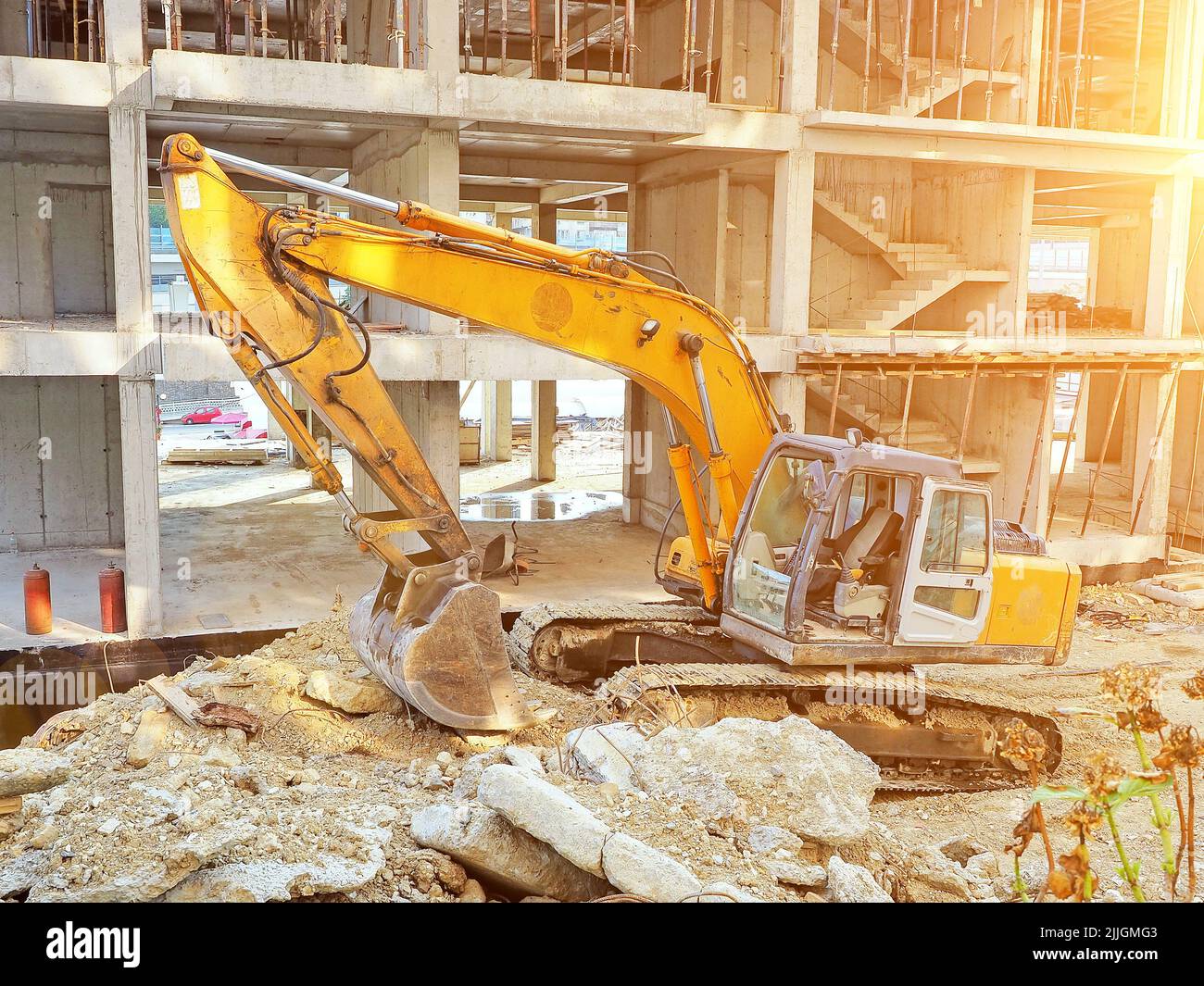 Yellow excavator without a driver in a pile of broken concrete and sand ...