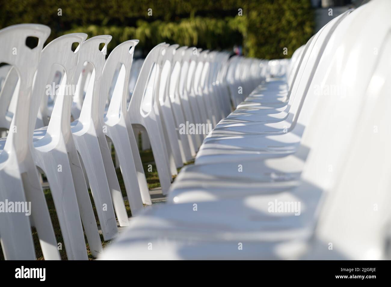 Many white plastic chairs were set up in a square area with the row and ...