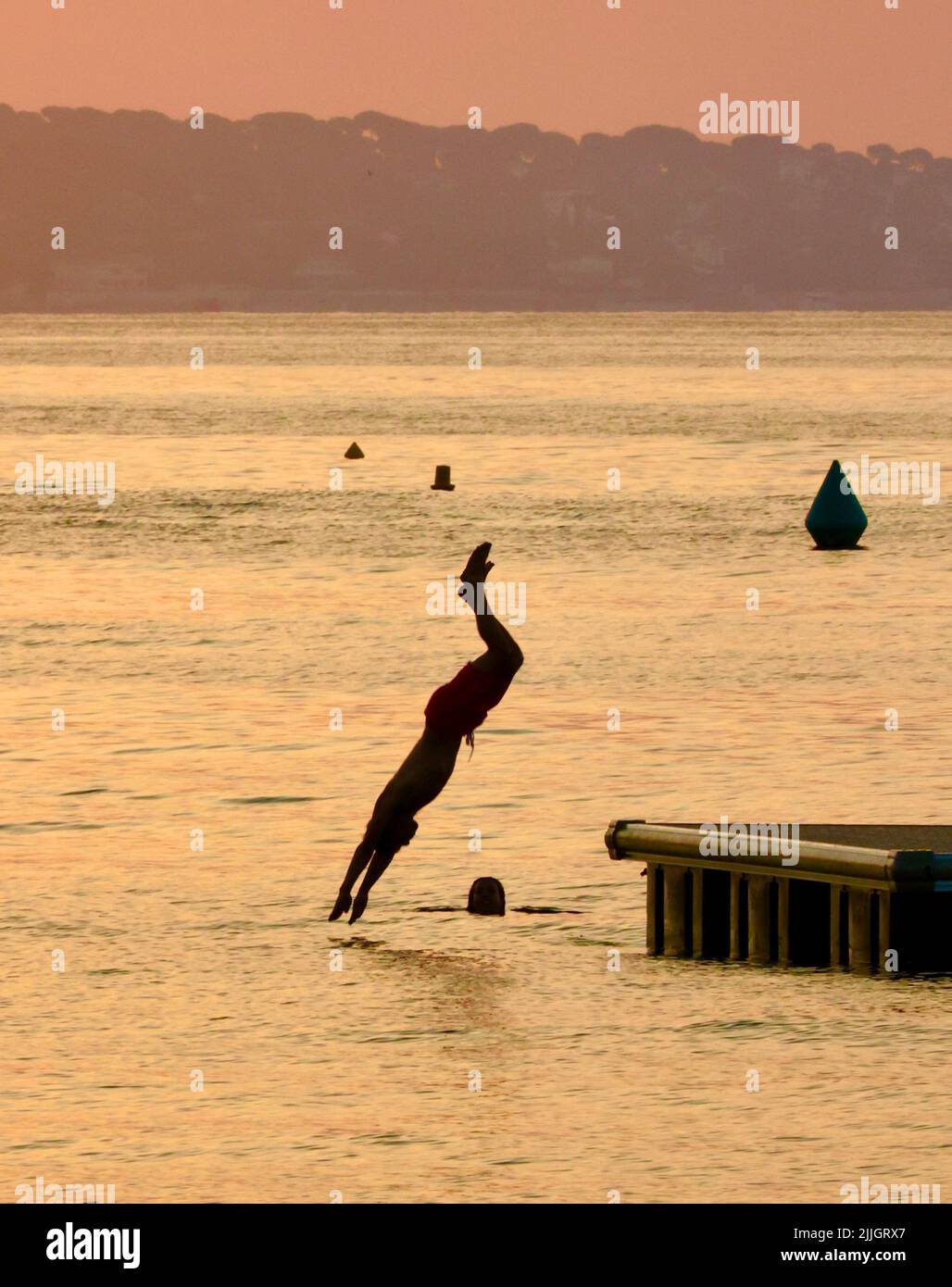 The man diving into the water from dock at the sunset Stock Photo - Alamy