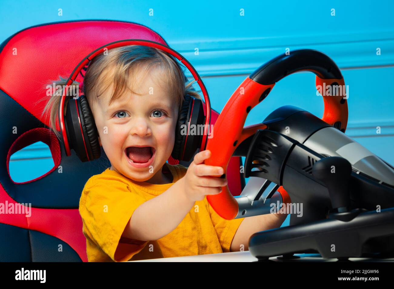 Baby girl in headphones with steering wheel play race game Stock Photo ...