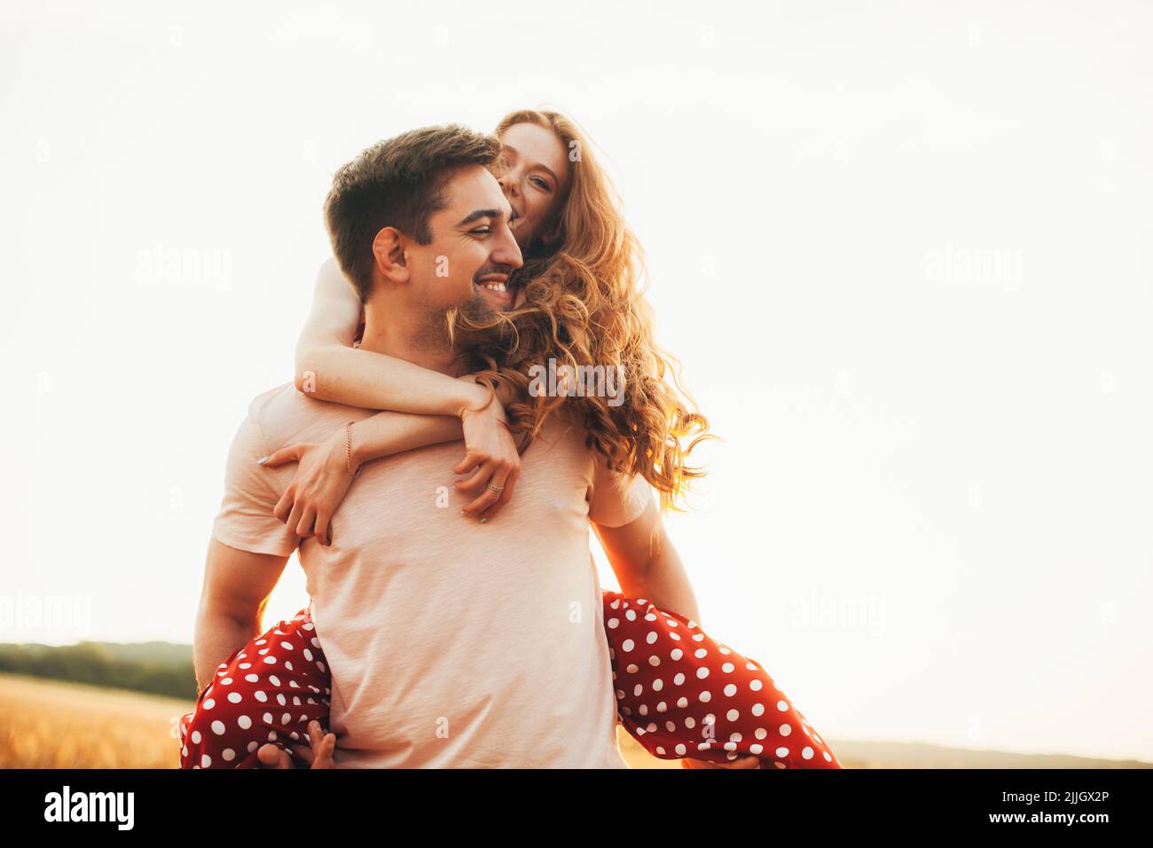 Portrait of a man giving to his girlfriend a piggy-back ride in an ...