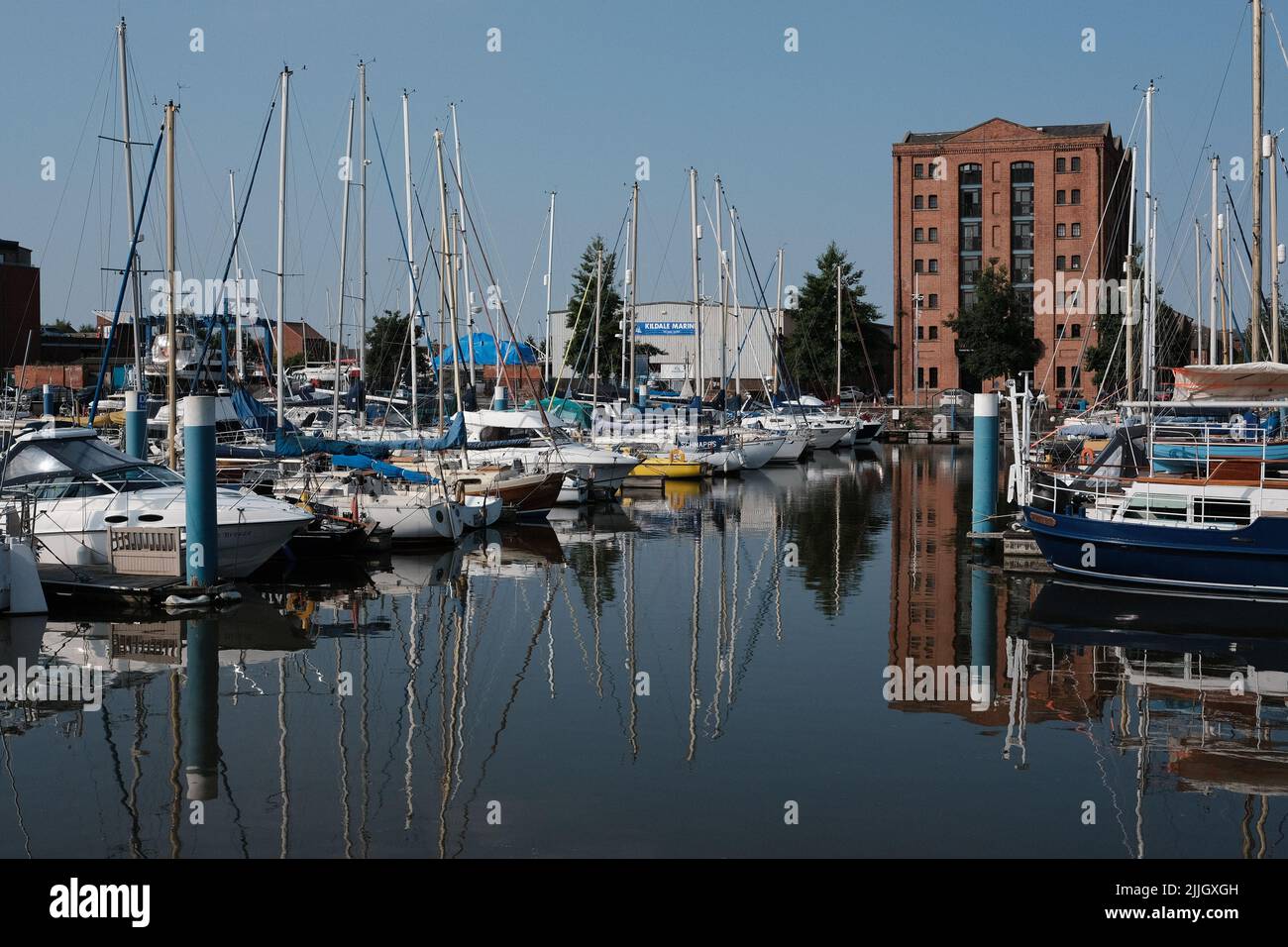 Boats and yachts with reflections of boats, masts, and buildings on ...