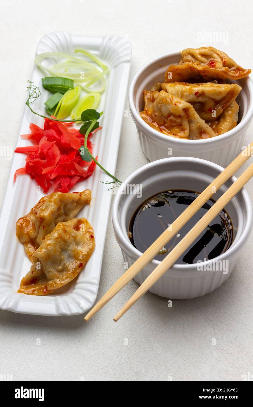 Chopsticks on bowl with soy sauce. Pickled ginger, chopped leeks and ...