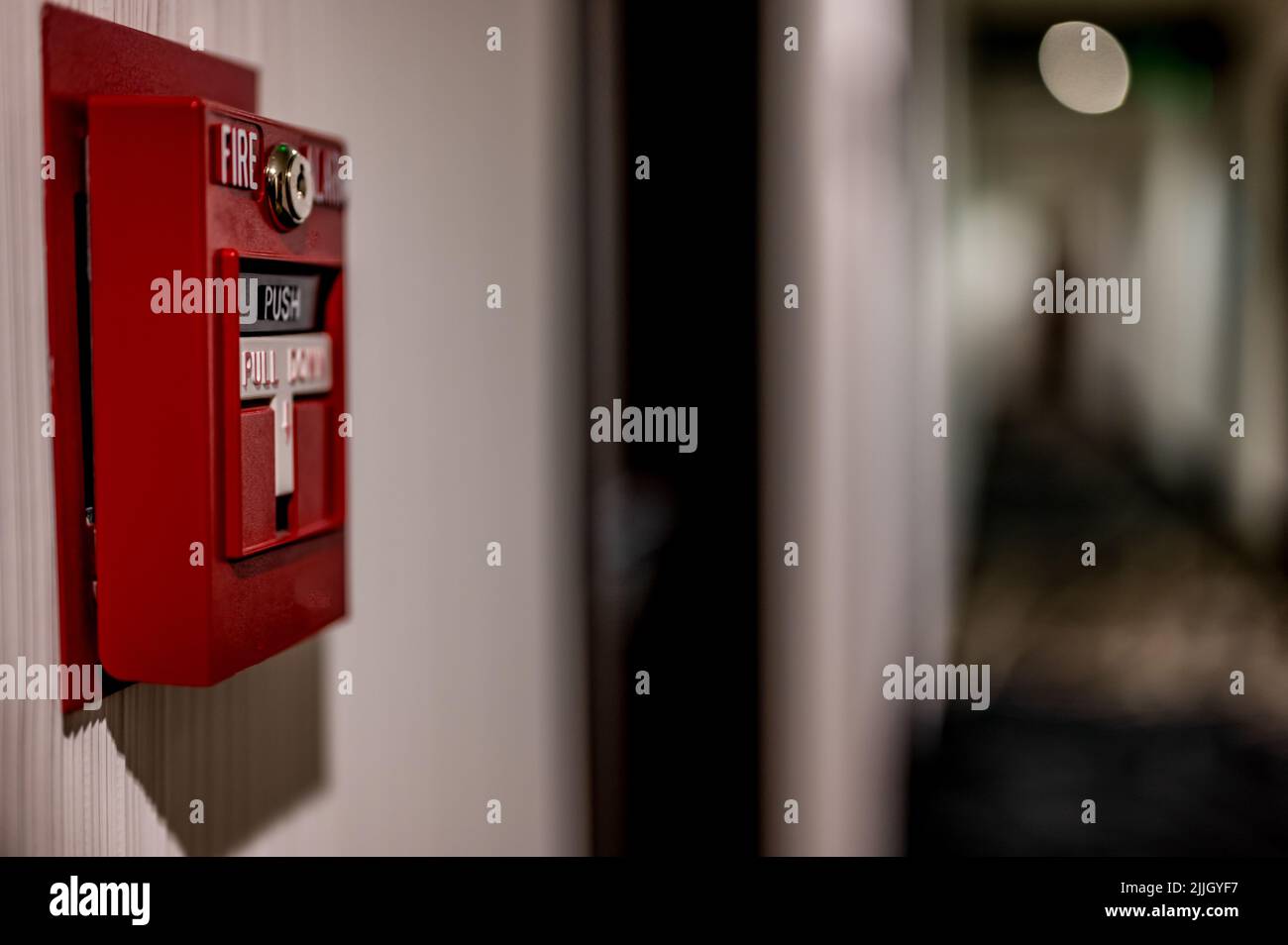 Selective focus on a wall mounted fire alarm switch in a empty hallway ...