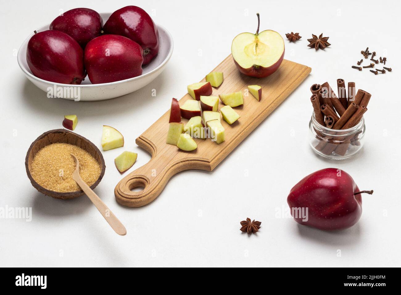 Chopped apples on cutting board. Brown sugar in coconut shell. Cinnamon ...