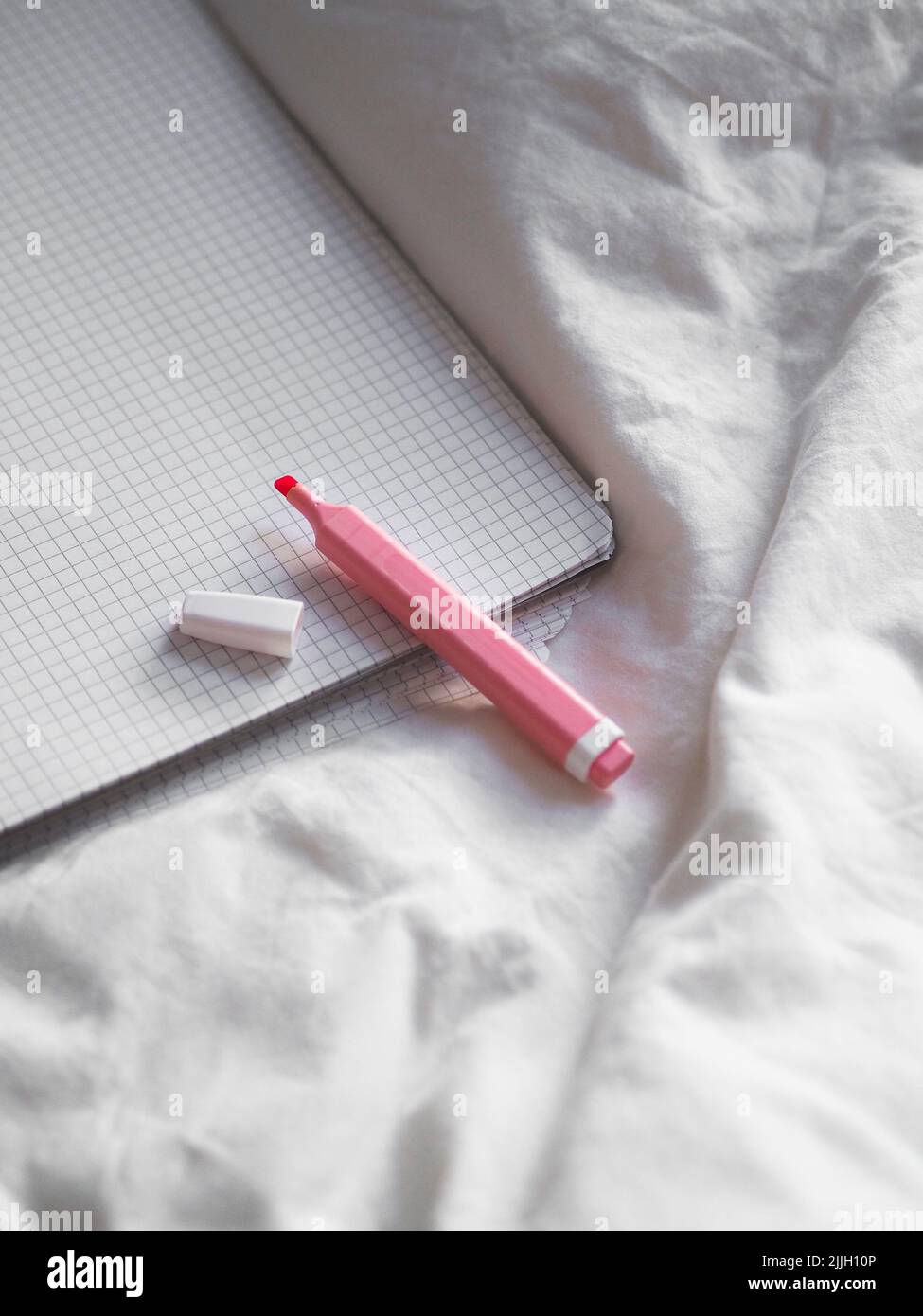 The vertical view of the pink highlighter pen on the squared paper of ...