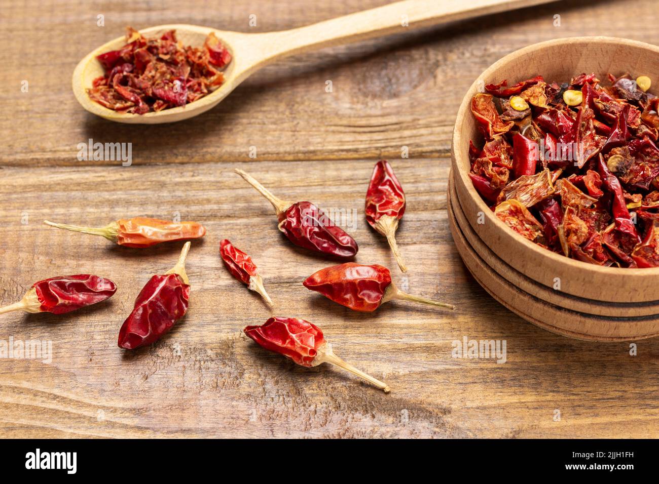 Pods of dry red pepper in wooden bowl and on table. Top view. Wooden ...