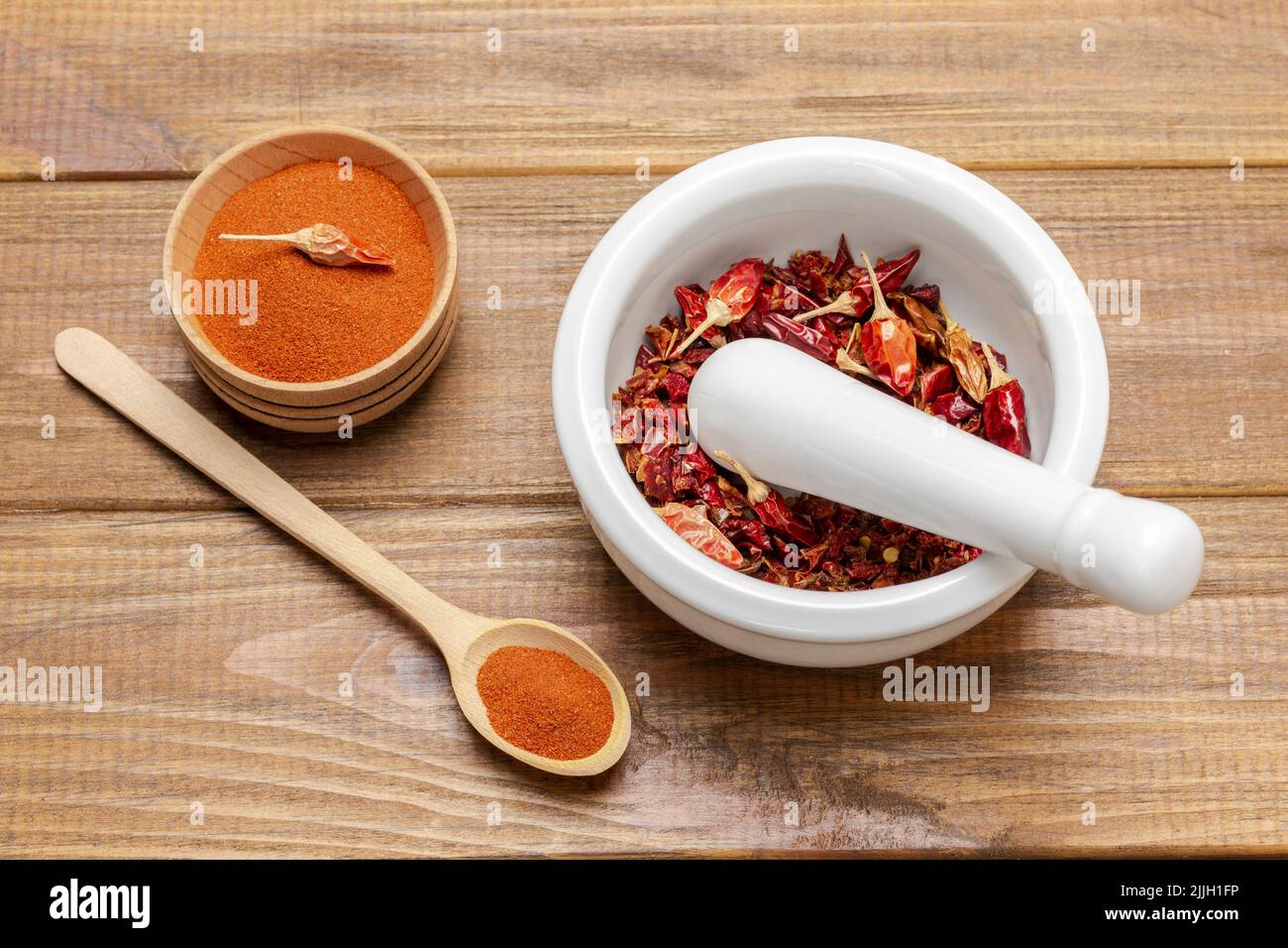 Dry red pepper pods in porcelain mortar. Ground red pepper in wooden ...
