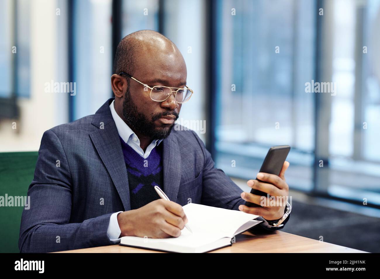 African businessman in suit looking at the screen of mobile phone ...